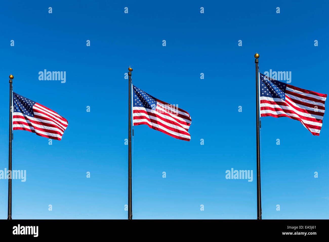 Three American flags against blue sky Stock Photo - Alamy