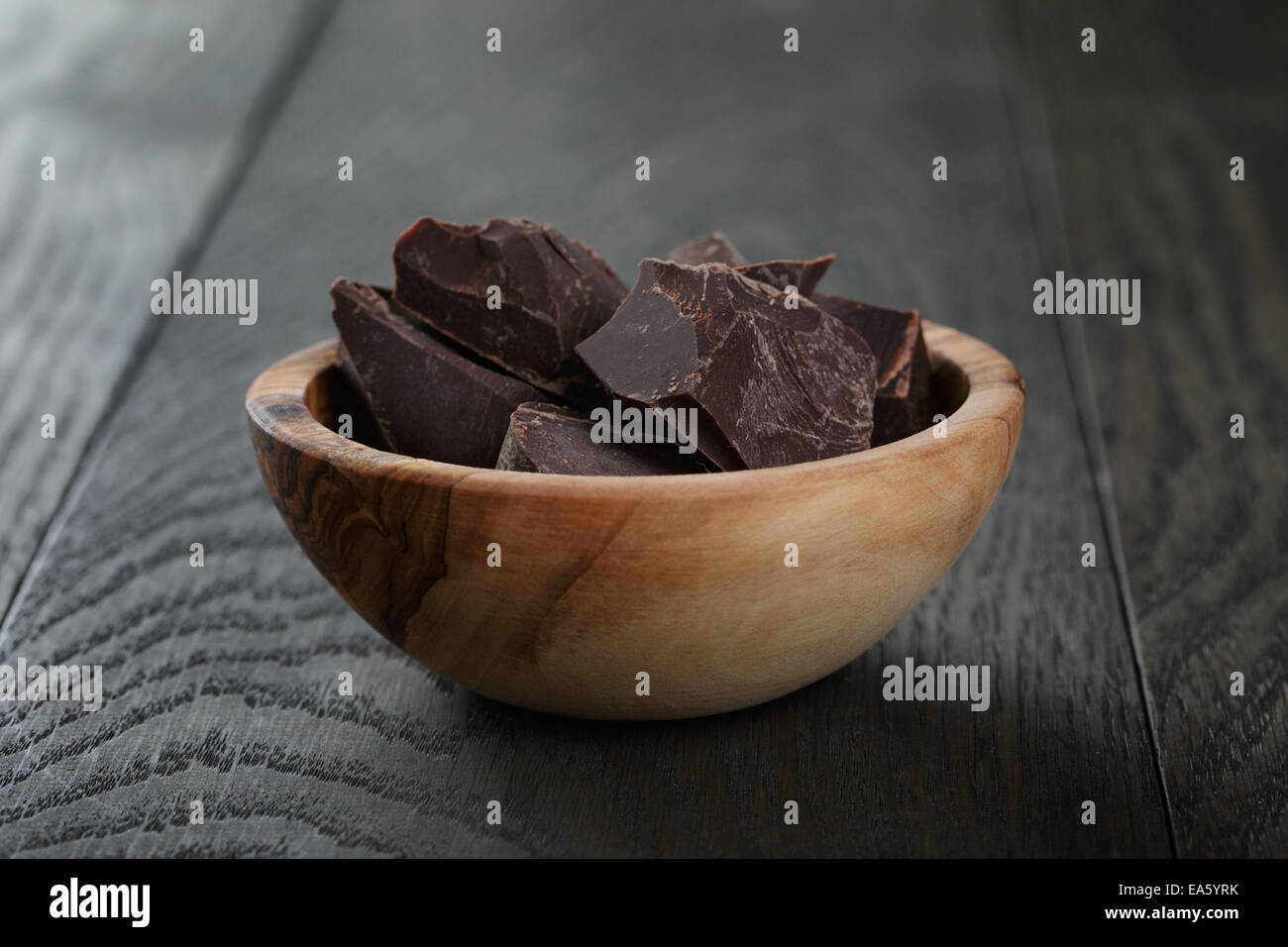 dark chocolate chunks in wooden bowl, on oak table Stock Photo - Alamy