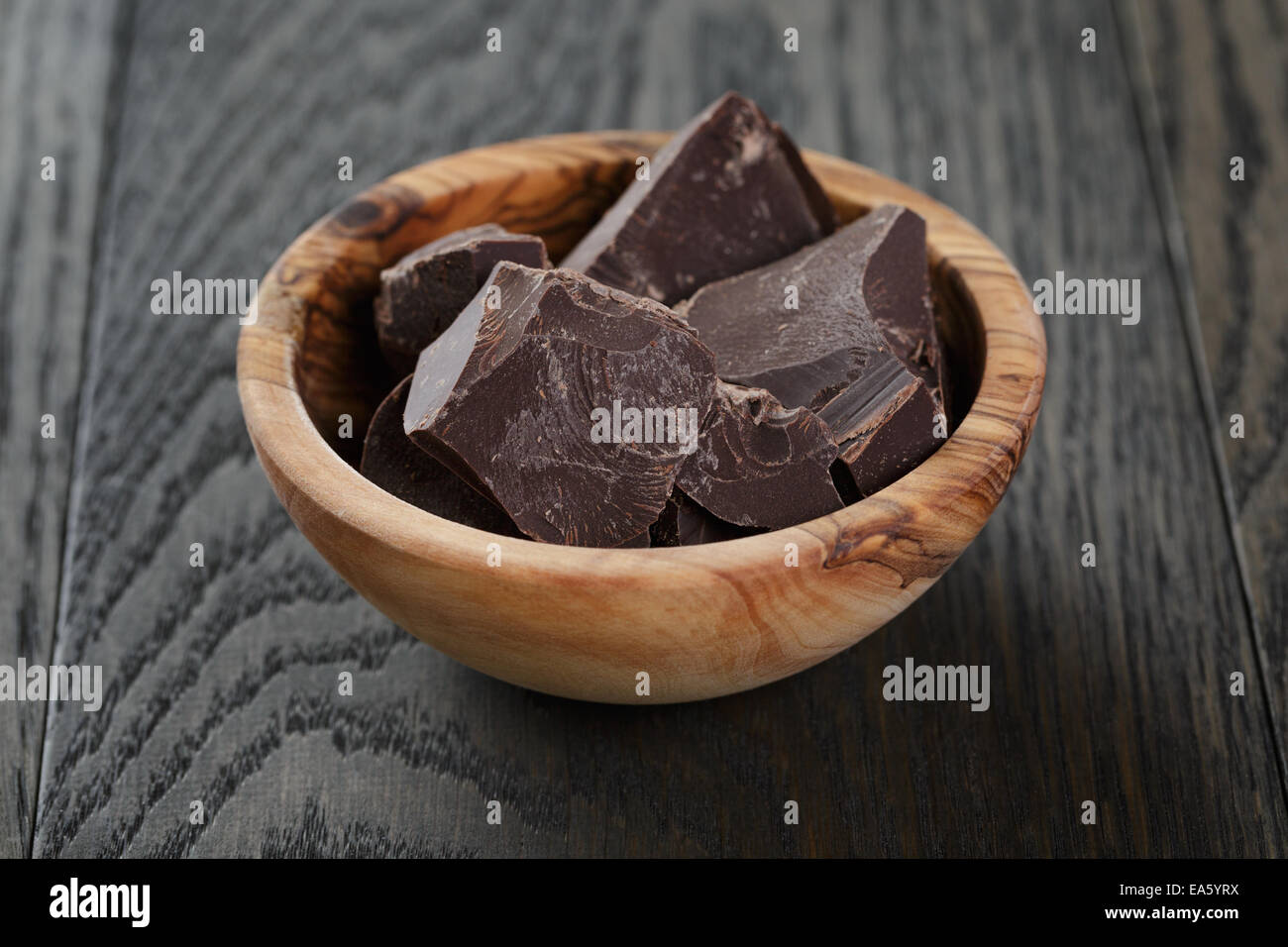 dark chocolate chunks in wooden bowl, on oak table Stock Photo - Alamy