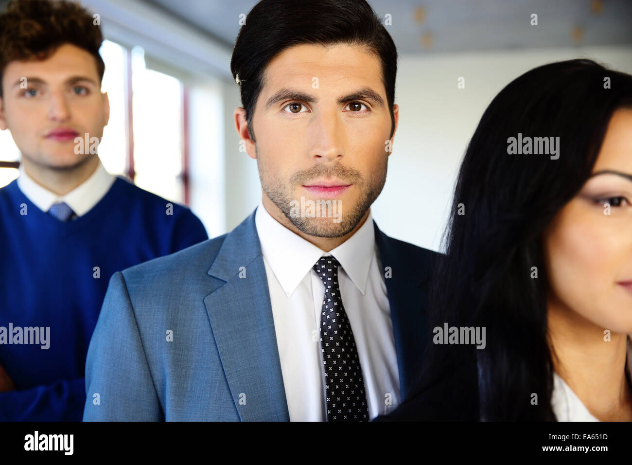 Group of a young serious businesspeople standing in office Stock Photo ...