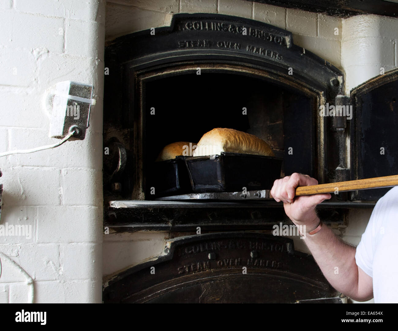Freshly baked bread being removed from a traditional, old oven by a ...