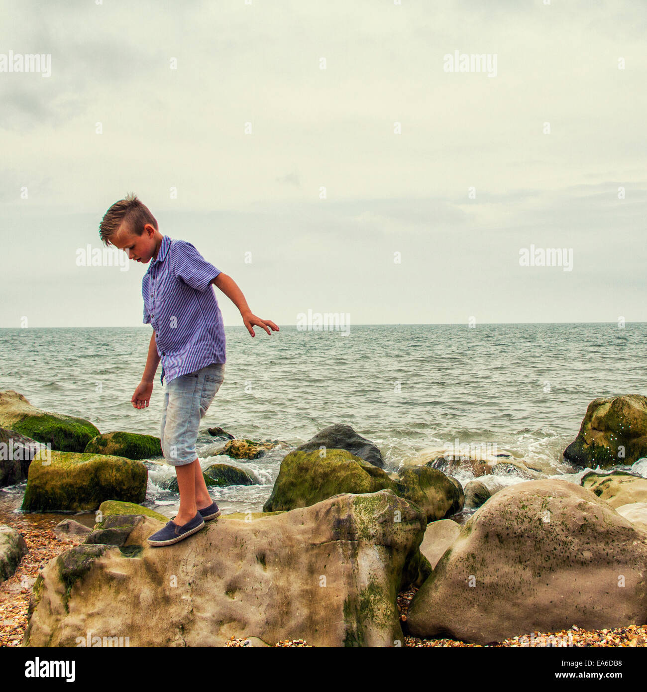 Boy walking on rocks by sea Stock Photo - Alamy