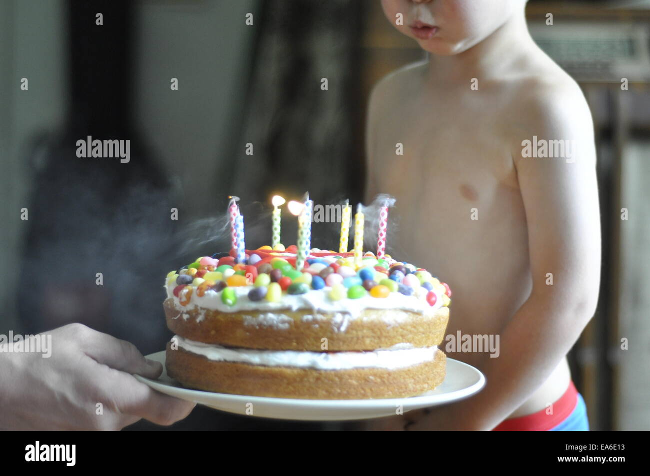 Boy blowing out candles on his birthday cake Stock Photo - Alamy