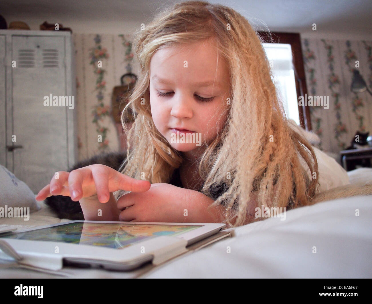 Girl lying on bed using digital tablet Stock Photo - Alamy