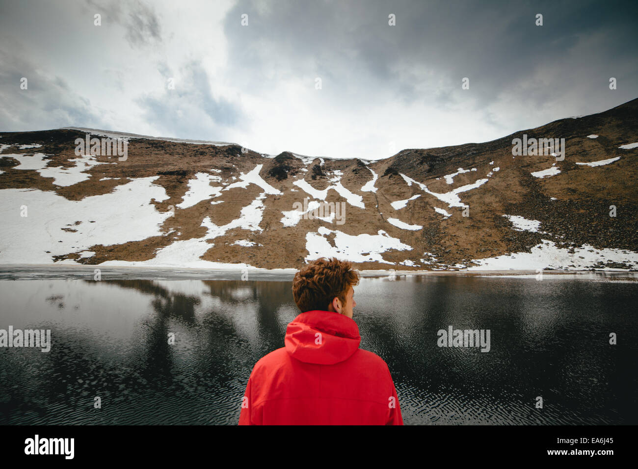 Back view of young man looking at mountain lake Stock Photo - Alamy