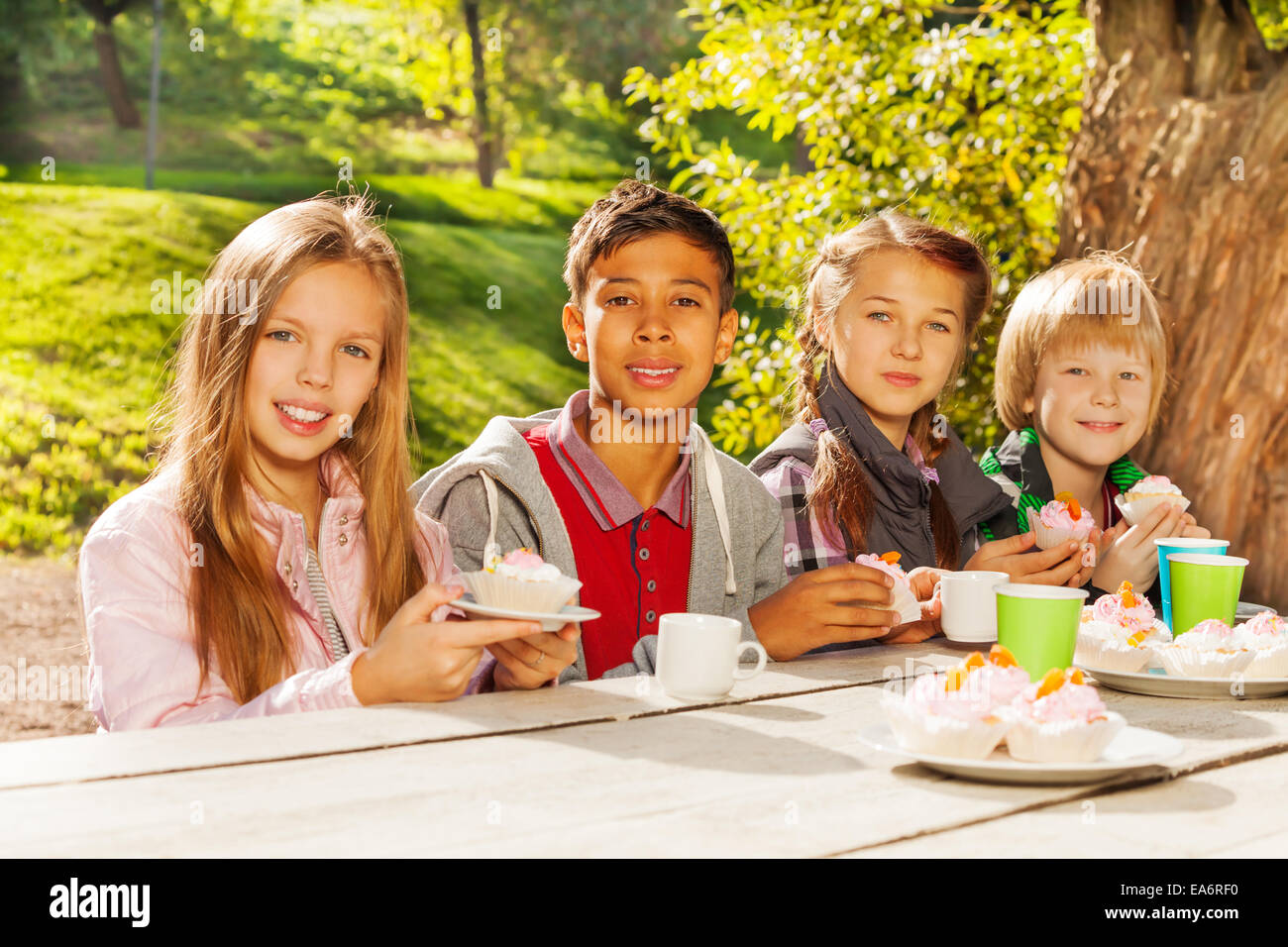 Happy children drinking tea with cupcakes Stock Photo - Alamy
