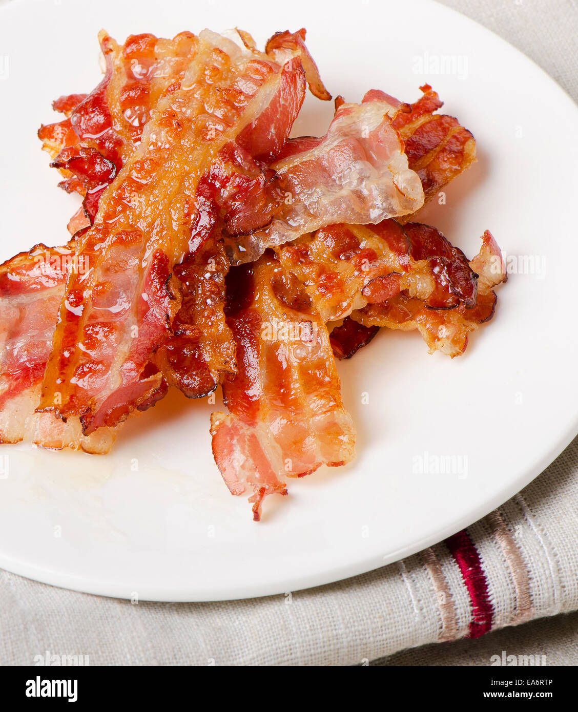 Cooked bacon rashers on a white plate. Selective focus Stock Photo - Alamy