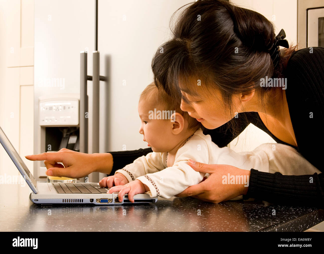 busy young korean asian mum using laptop computer in modern kitchen ...