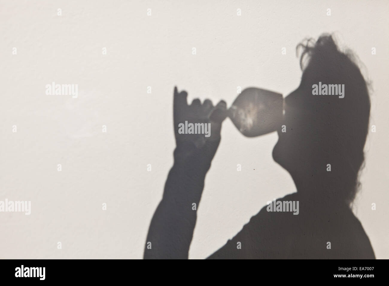 Wall shadow of woman drinking from wine glass Stock Photo - Alamy