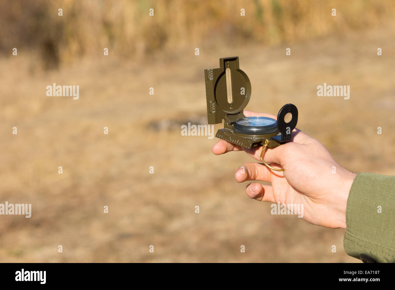 Young man holding a magnetic compass as he stands outdoors in the ...