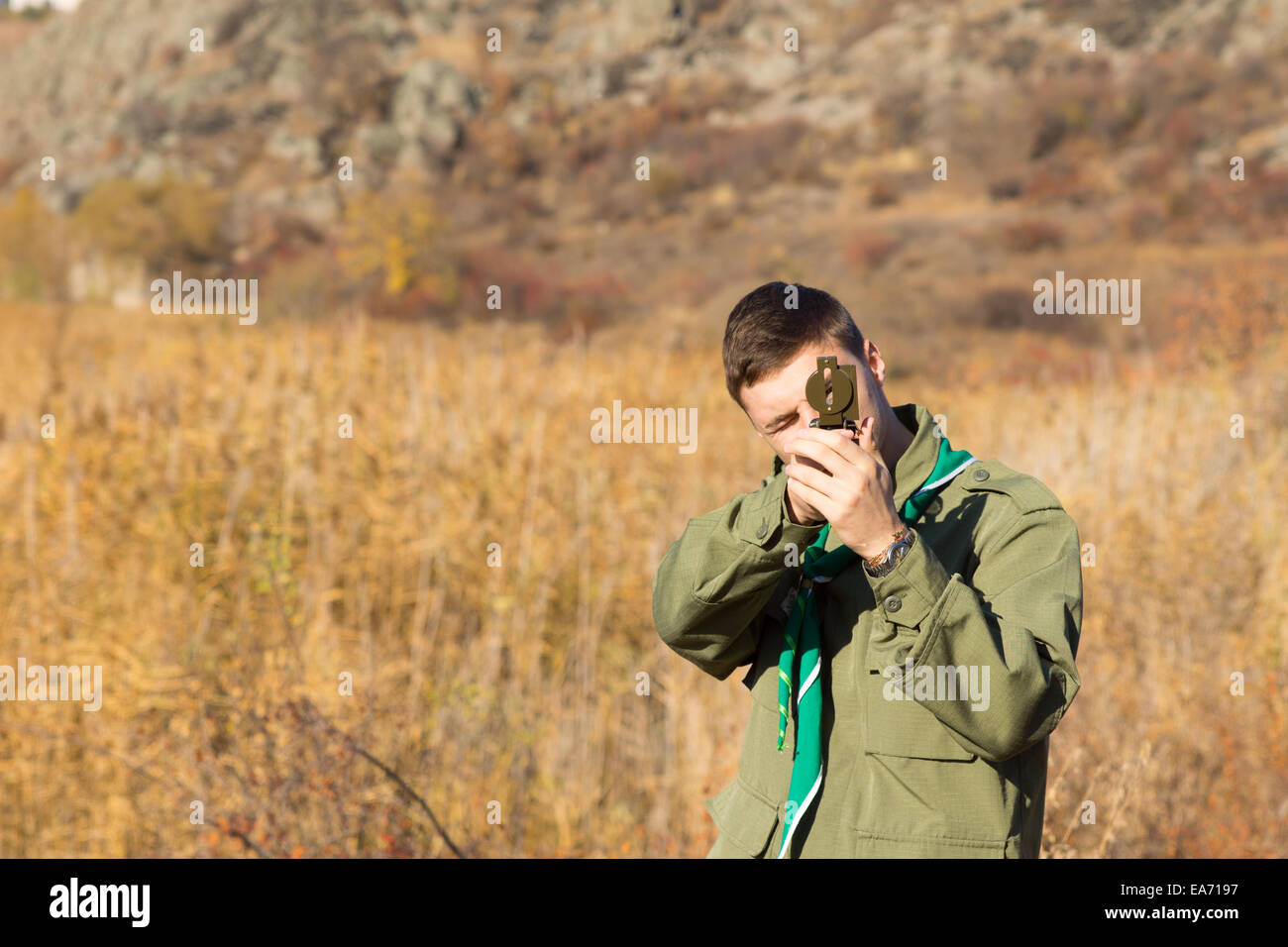 Scout taking a reading on his compass sighting on the camera as he ...