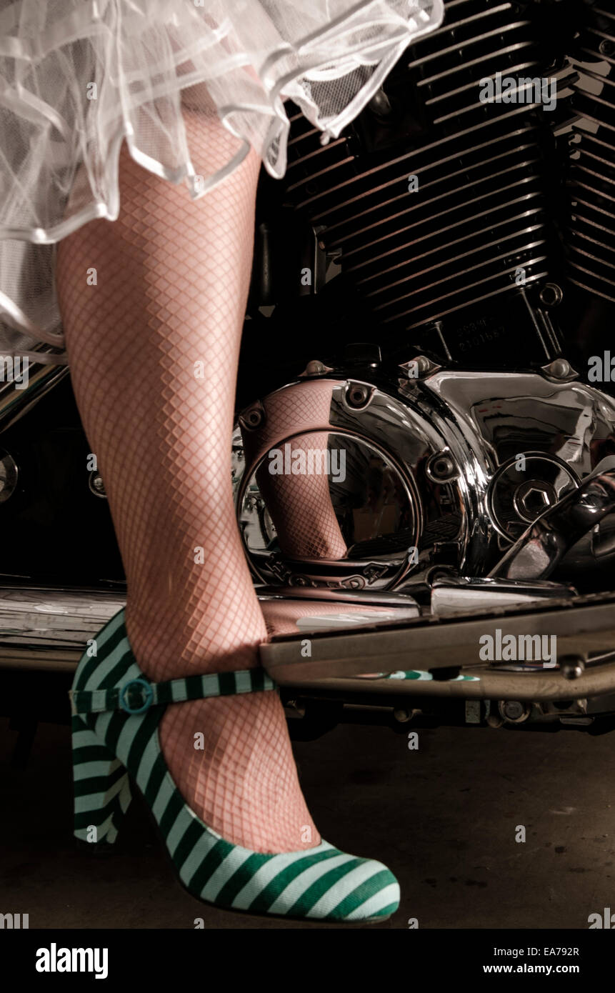 Cropped shot of woman's leg against background of motorcycle engine ...
