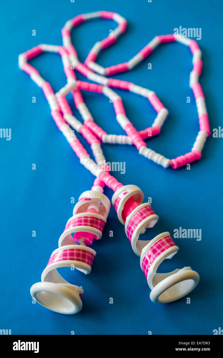 Pink and white toy jump rope on a blue background Stock Photo - Alamy
