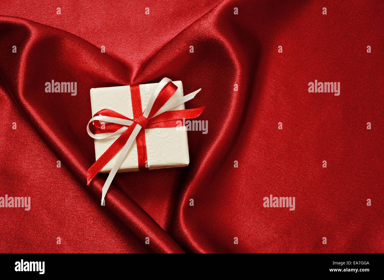Gift box on red draped satin Stock Photo - Alamy