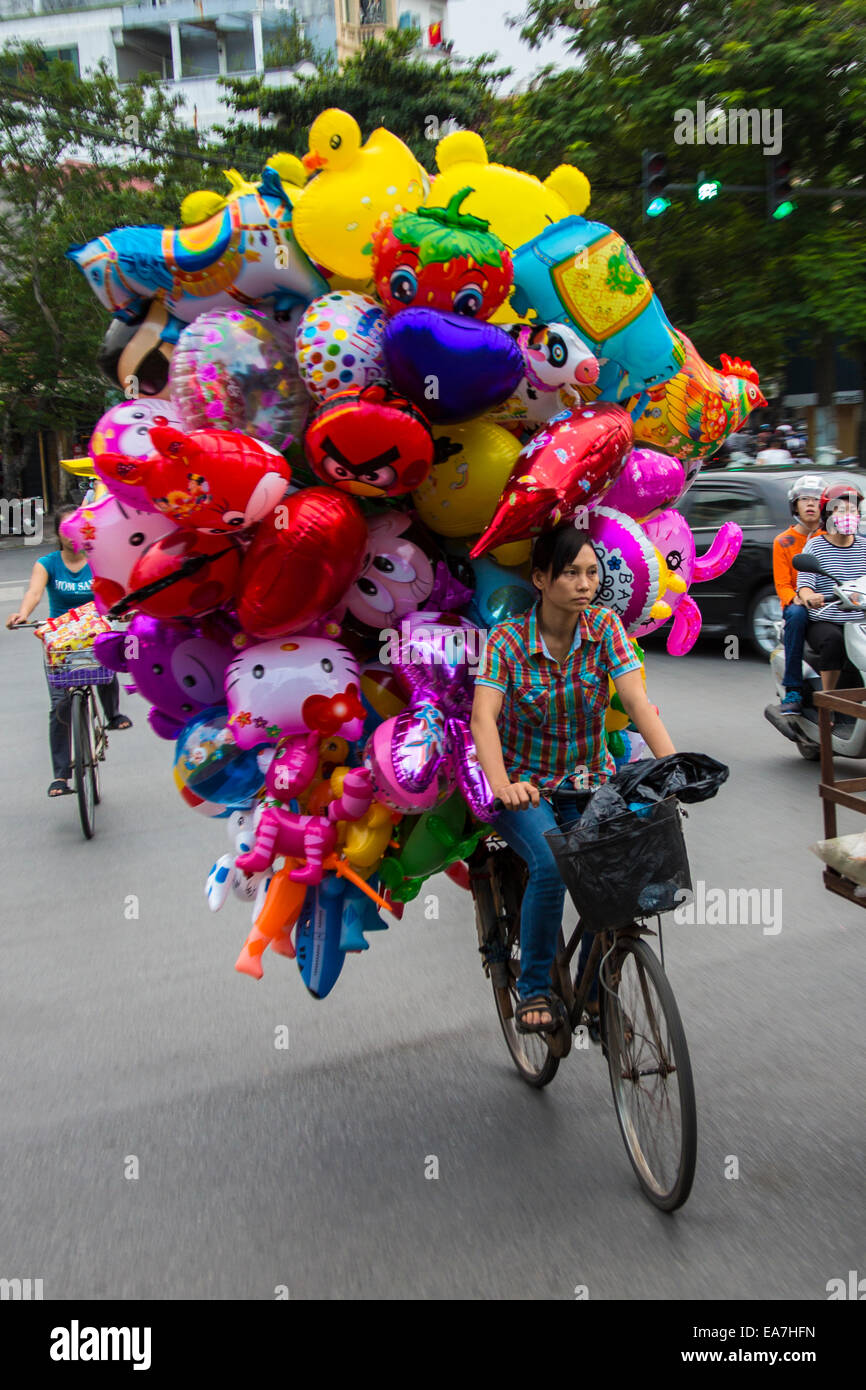 Woman rides bicycle laden with balloons Stock Photo - Alamy
