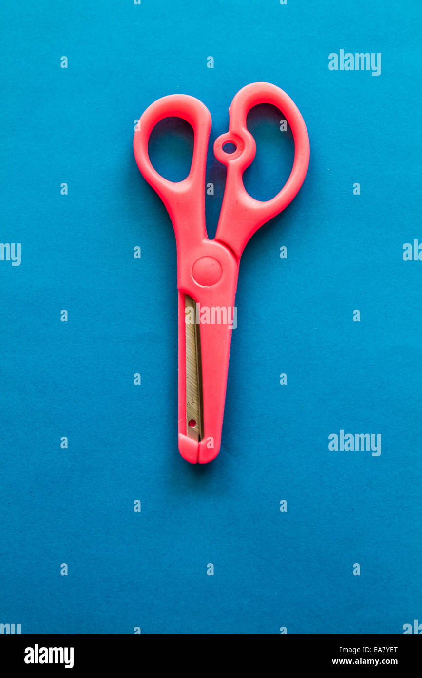 Pink toy scissors on a blue background Stock Photo - Alamy