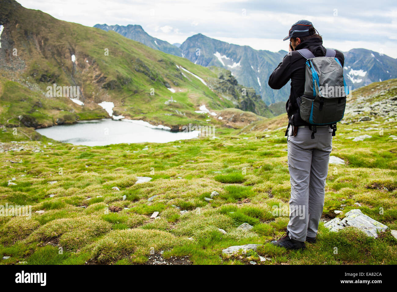 Hiking tourist taking photos of the alpine landscape Stock Photo - Alamy