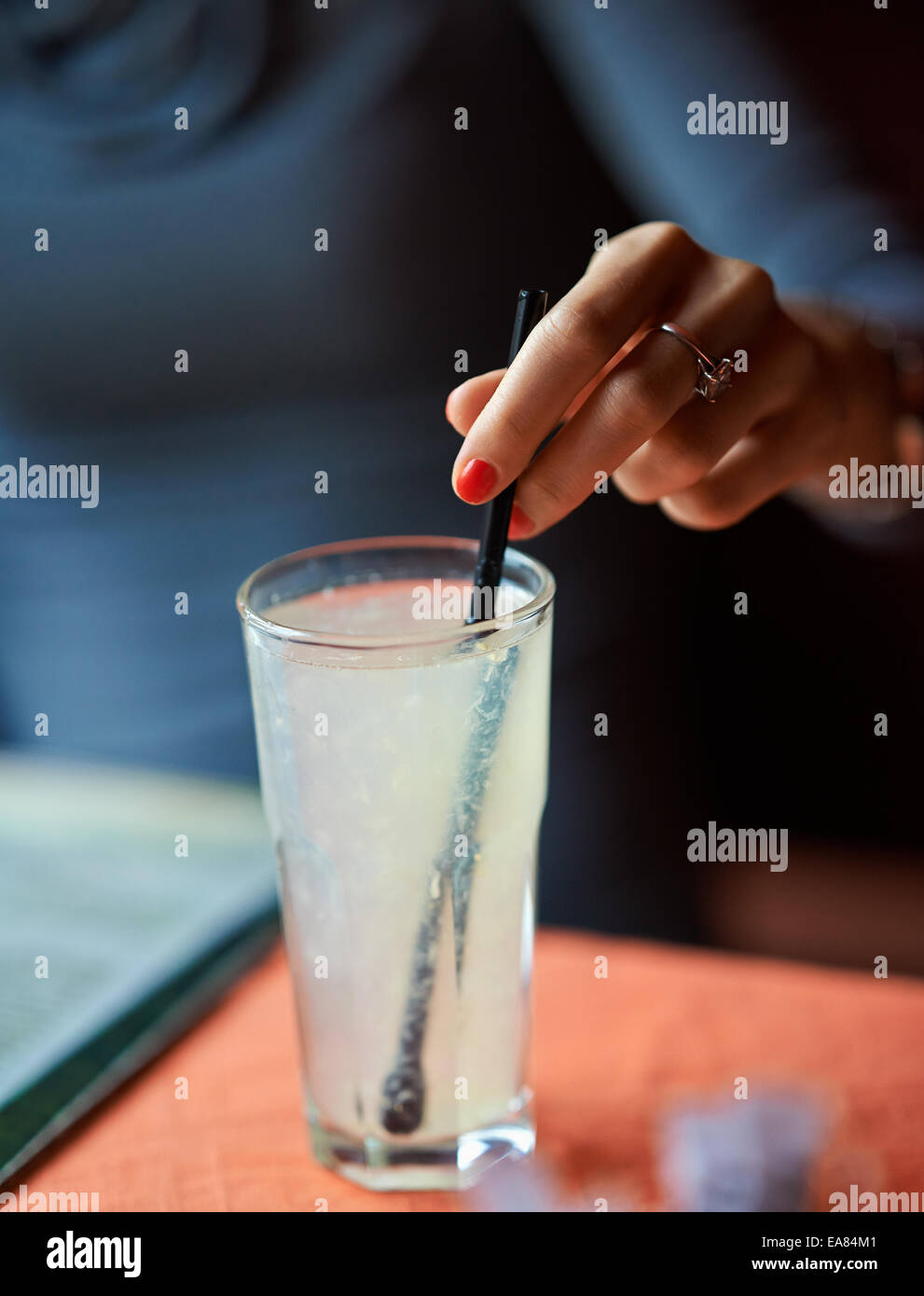 Woman's hand stirring in a glass of fresh lemonade Stock Photo - Alamy