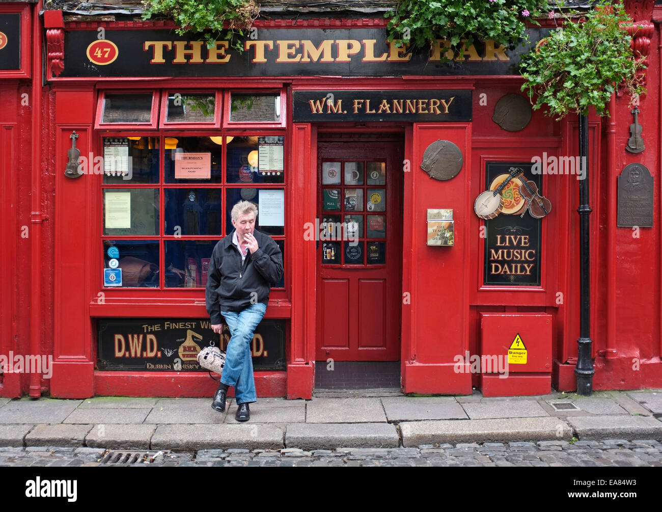 a man smokes outside the temple bar pub in temple bar , dublin, ireland ...