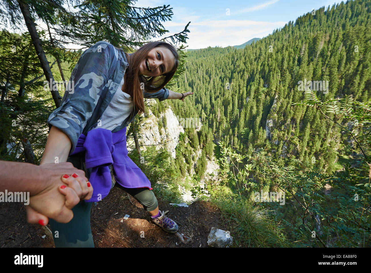 Man holding woman's hand while she leans over the very high cliff Stock ...