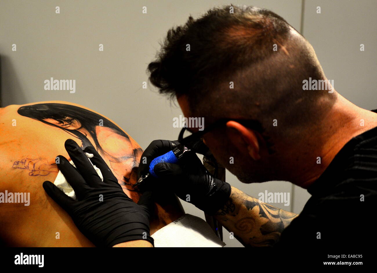 Tattoo artist tattooing portrait on back of woman Stock Photo - Alamy