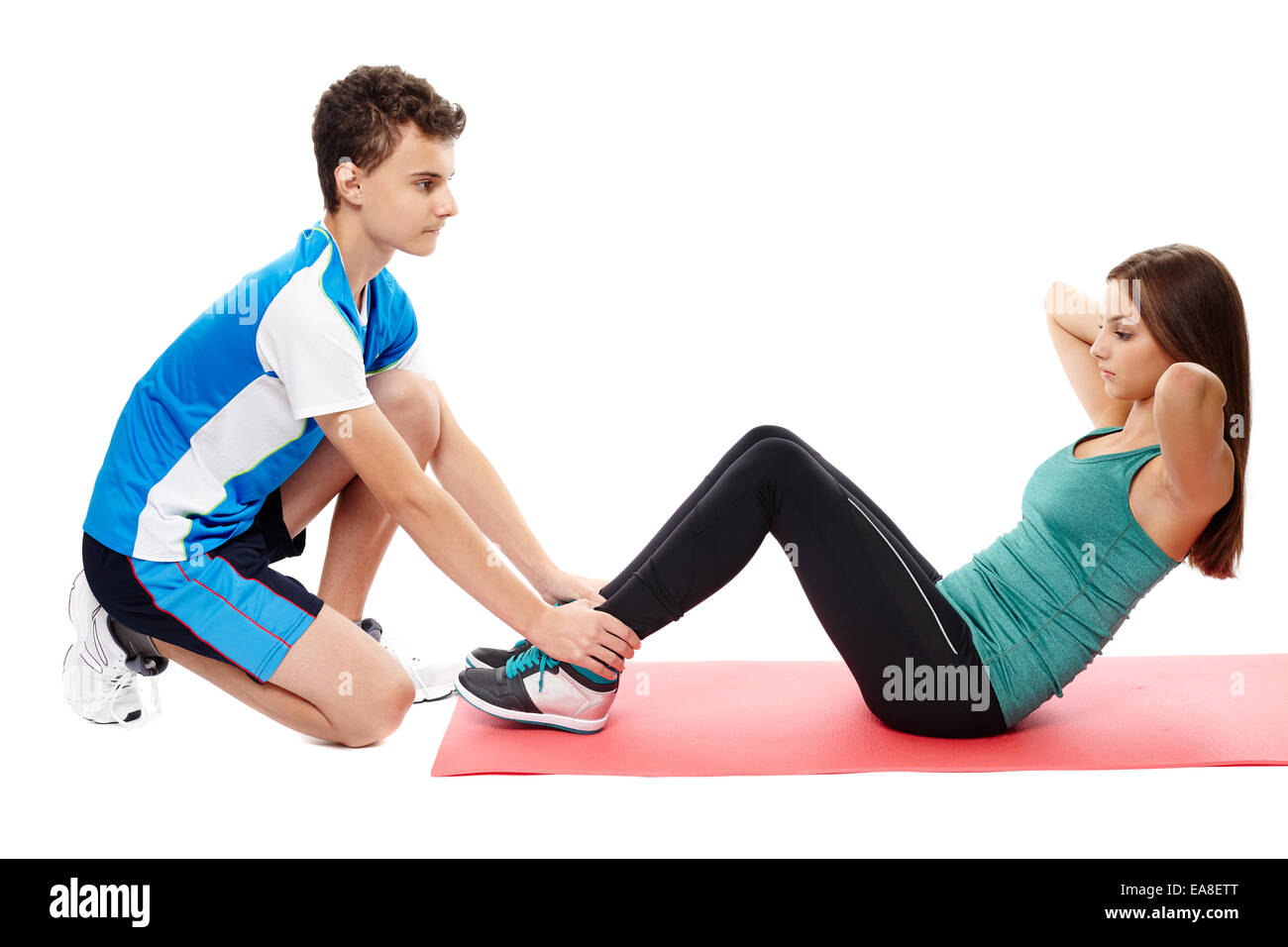 Teenagers boy and girl helping each other working out abs crunches on a ...