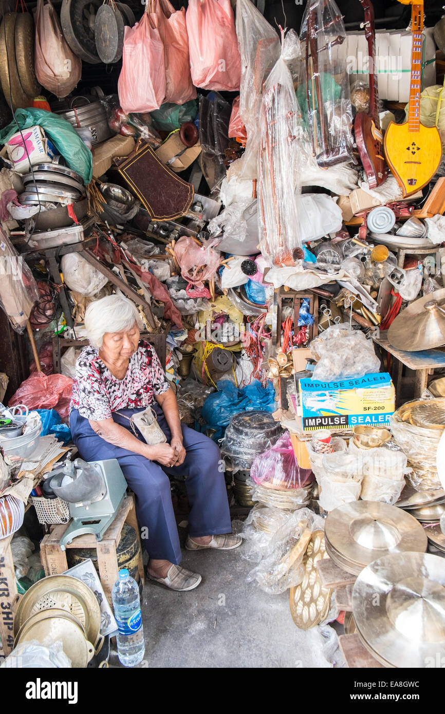 Saleswoman with disorganized stock of hardware goods,pots for sale at ...