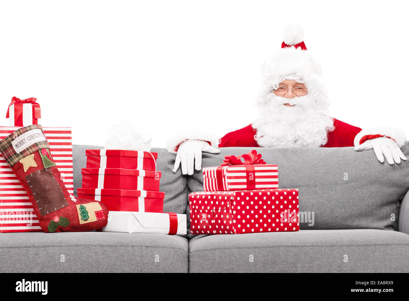 Santa Claus hiding behind a sofa full of Christmas presents isolated ...
