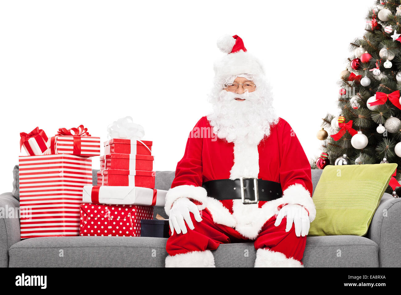 Santa sitting on a sofa by a Christmas tree isolated against white ...
