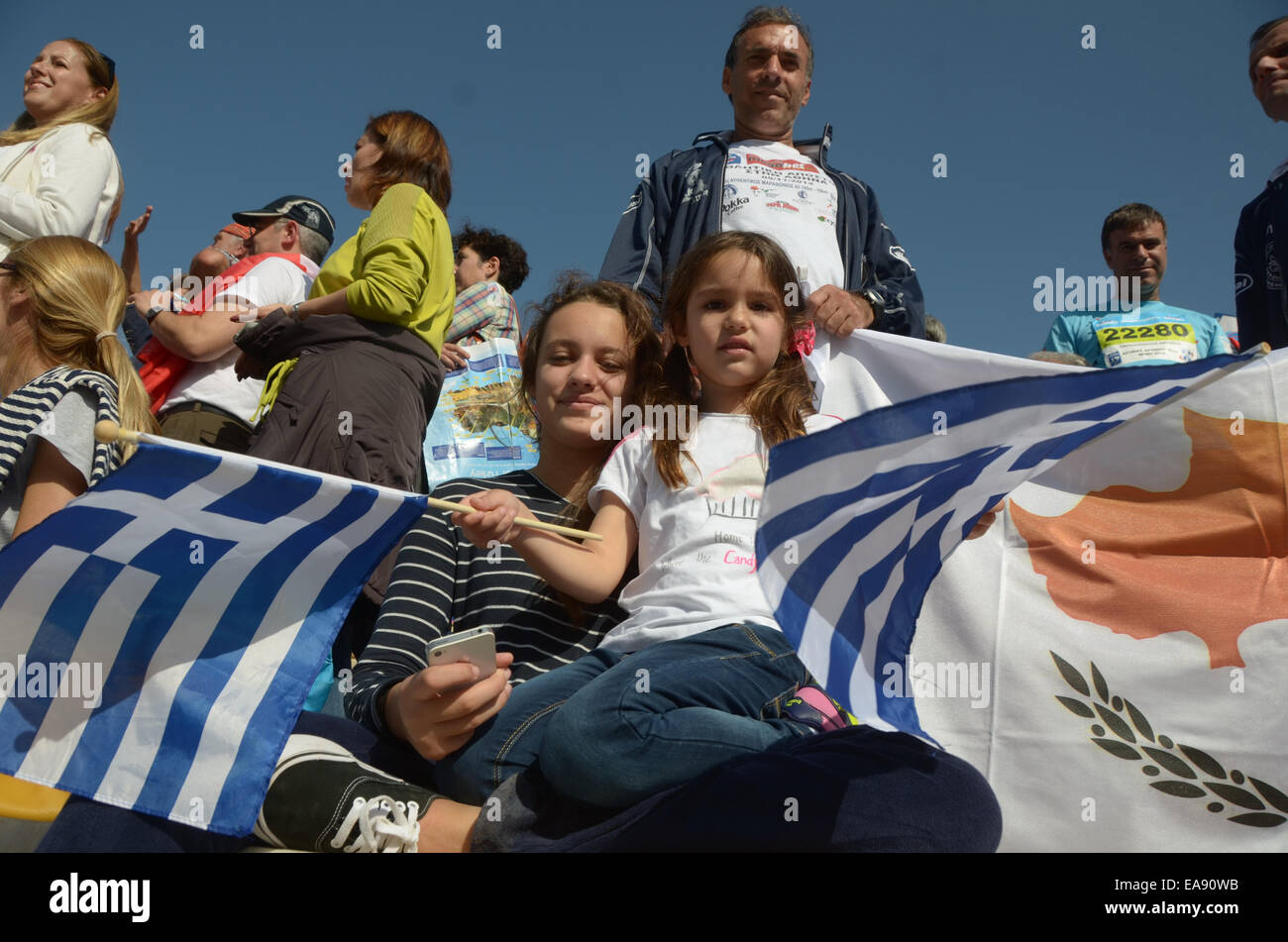 A small girl poses for the camera holding Greek flags. The 32nd Athens ...