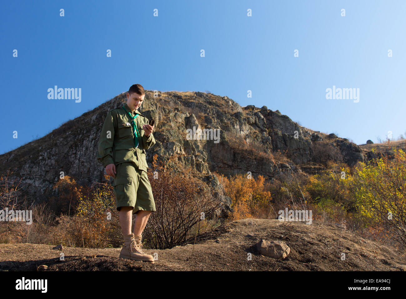 Boy scout or ranger out on a wilderness trail in his uniform standing ...