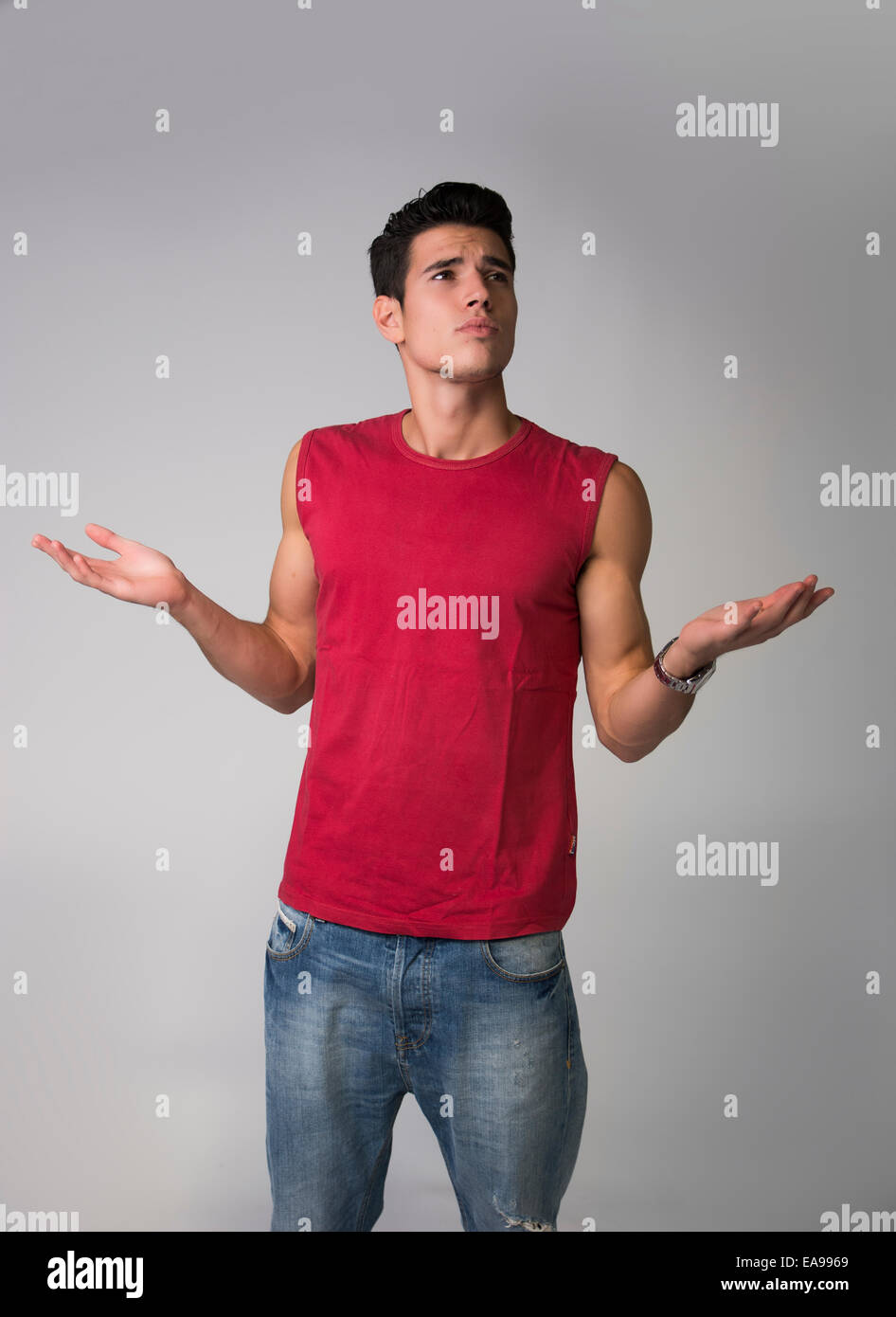 Handsome unsure, doubtful young man shrugging with arms open, looking ...