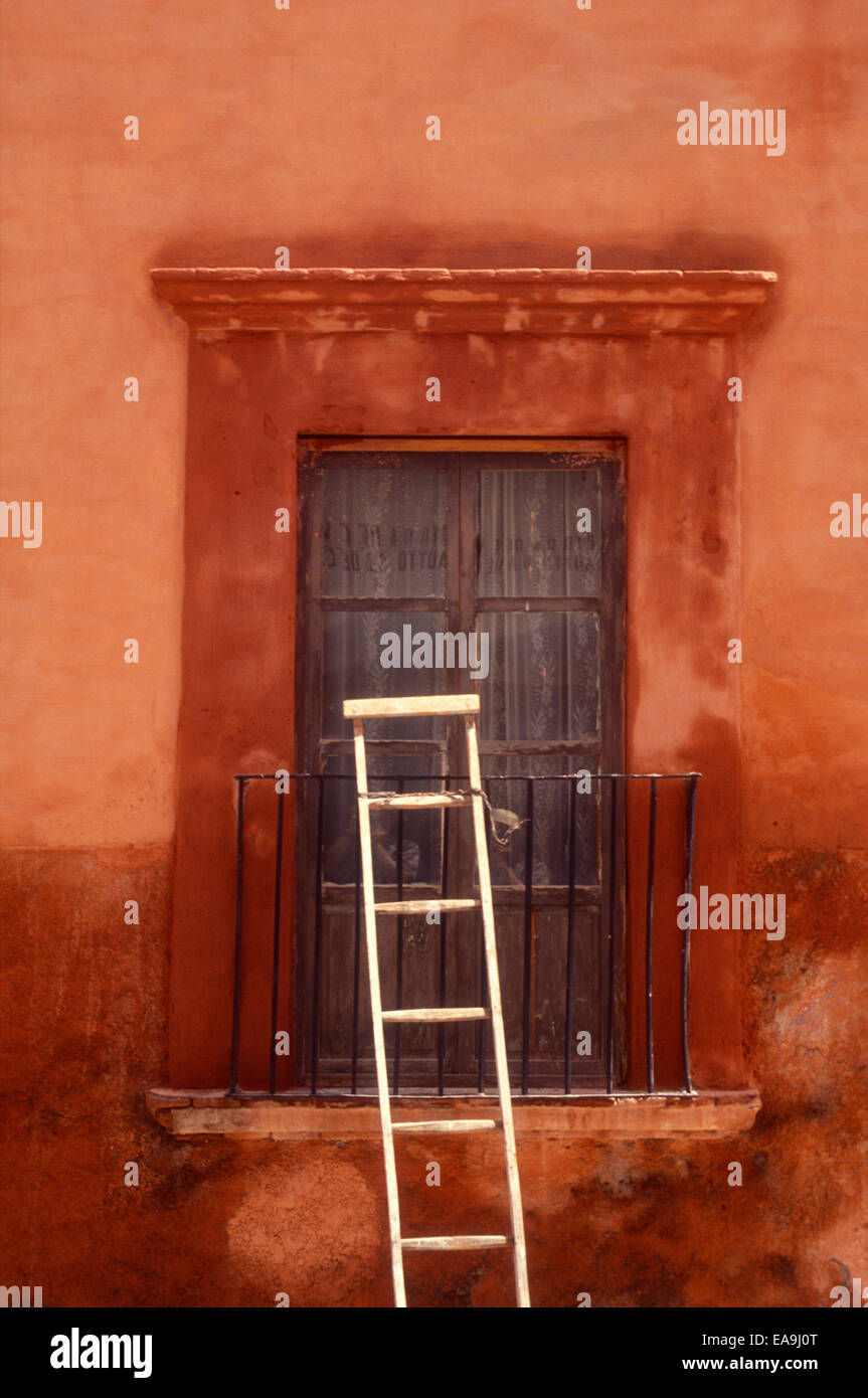 Wooden painter's ladder leaning against an iron balcony of a Spanish ...