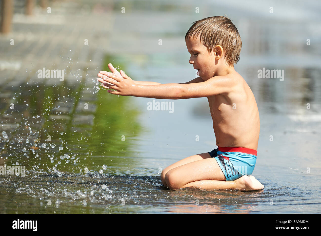 Little boy playing with water in a puddle in the park Stock Photo - Alamy