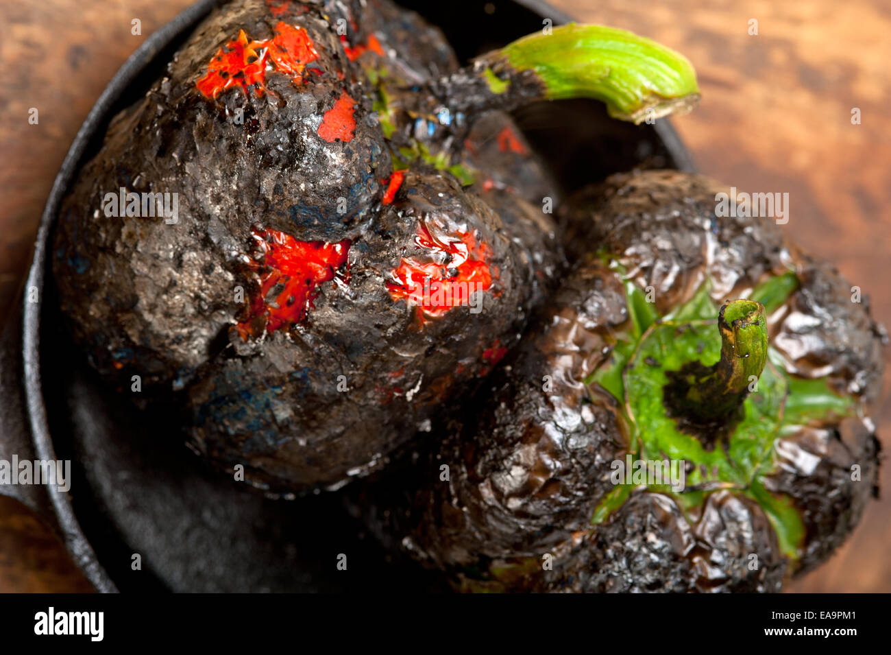 three fresh bell peppers charcol scorched over old wood table on a ...