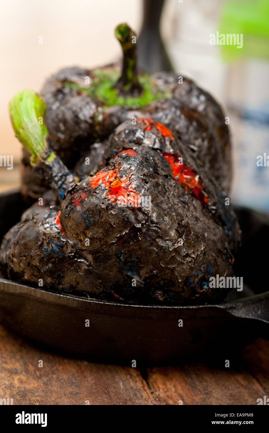 three fresh bell peppers charcol scorched over old wood table on a ...