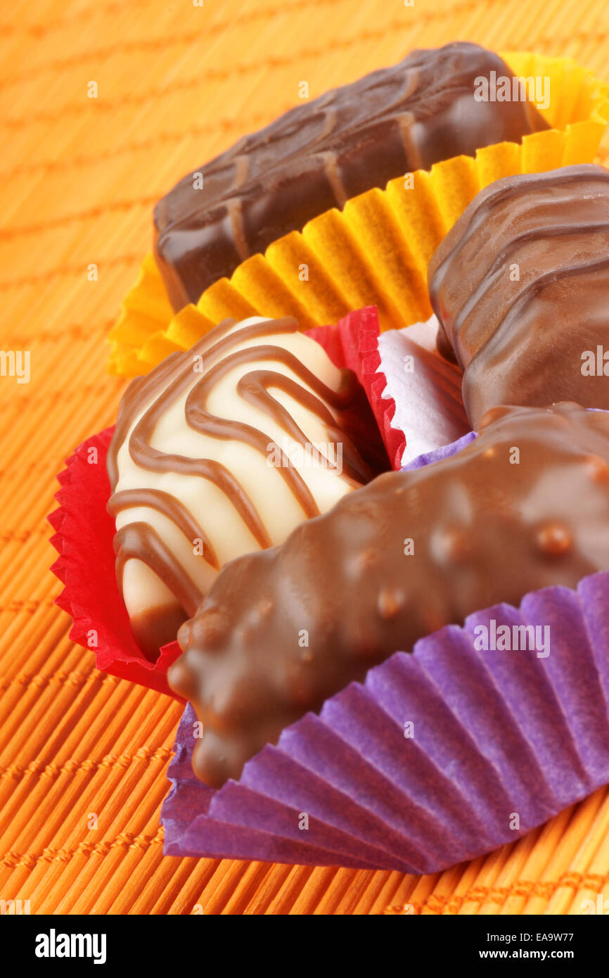 Closeup of some mixed chocolate pralines over an orange background ...