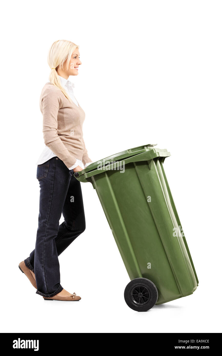 Cheerful young woman pushing a garbage can isolated on white background ...