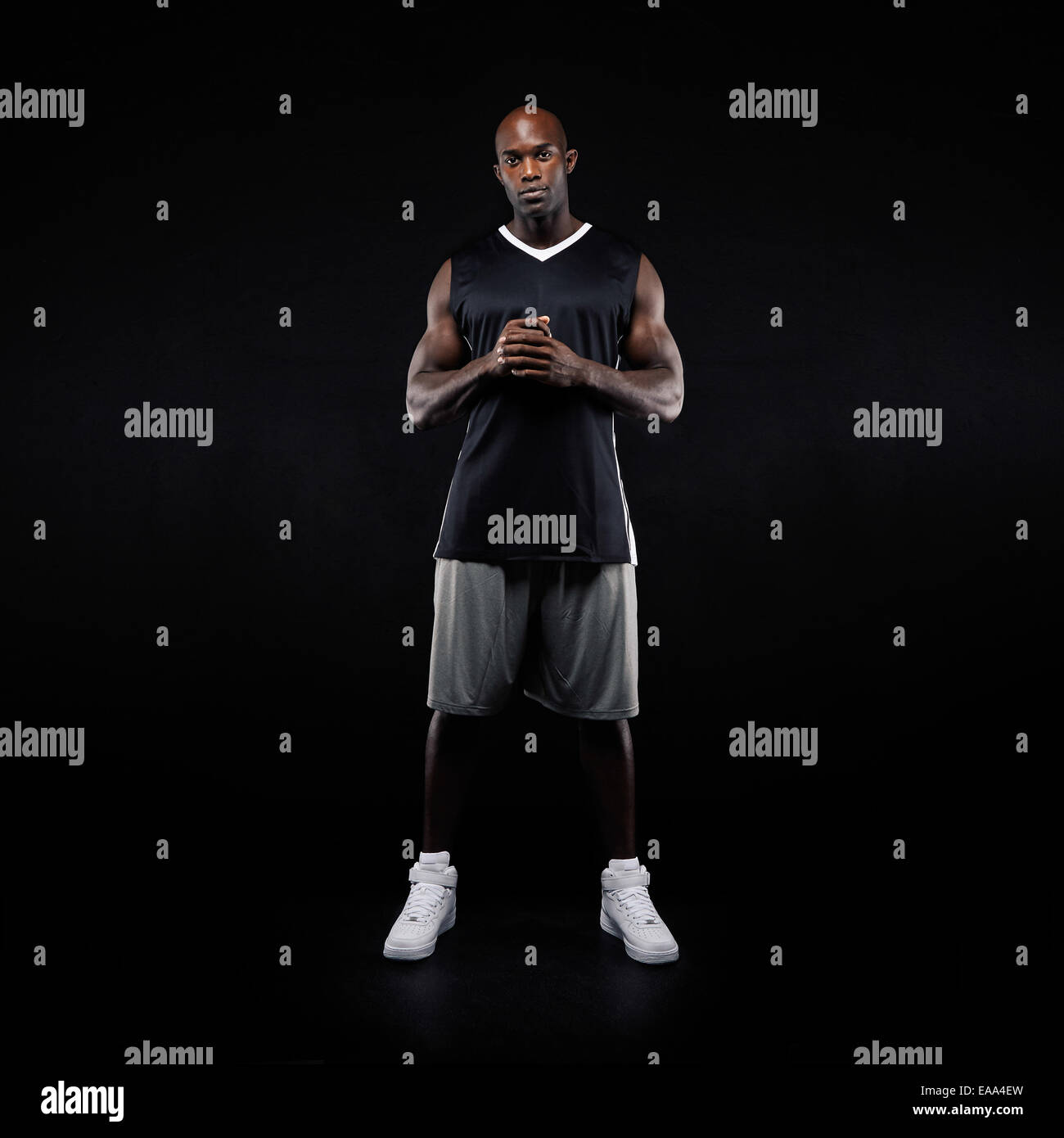 Full length image of young basketball player standing on black ...