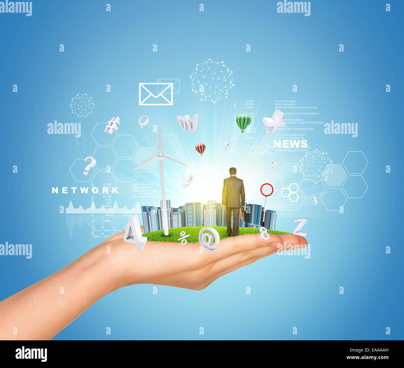 Hand holds city of skyscrapers on green grass and businessman walking ...