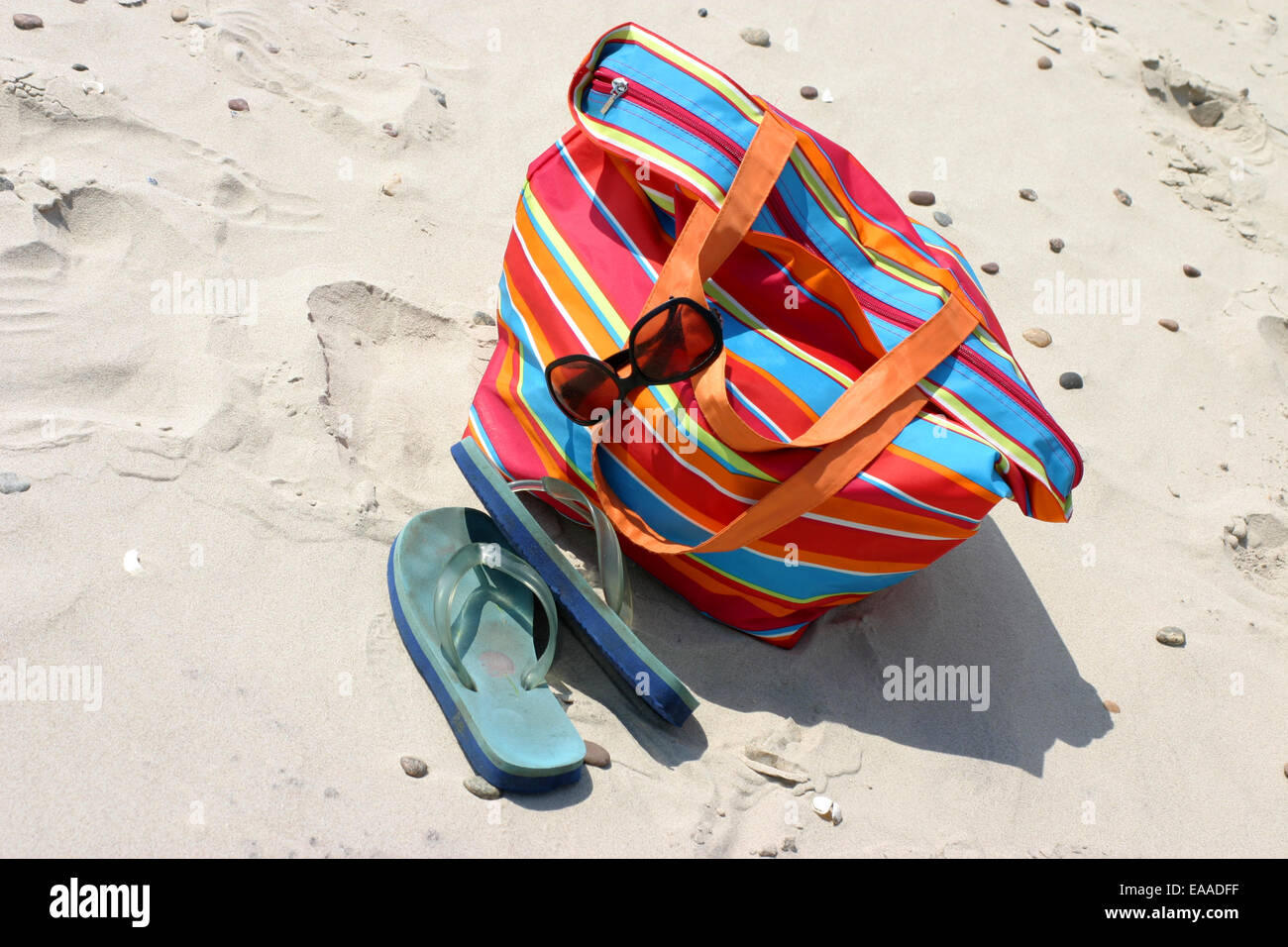 Beach items - flip flops, beach bag and sunglasses lying on the sand ...