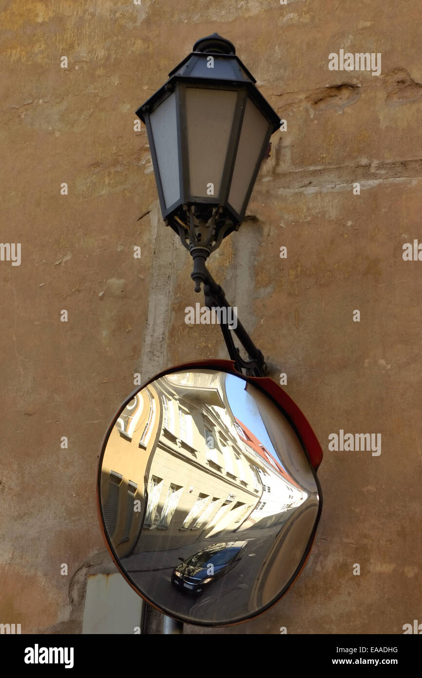 Blind driveway warning mirror with street lamp on the old town wall ...