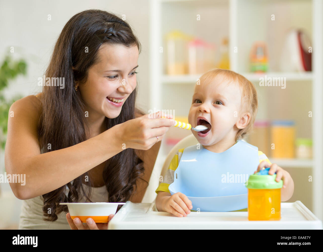Mum spoon feeding child son Stock Photo - Alamy