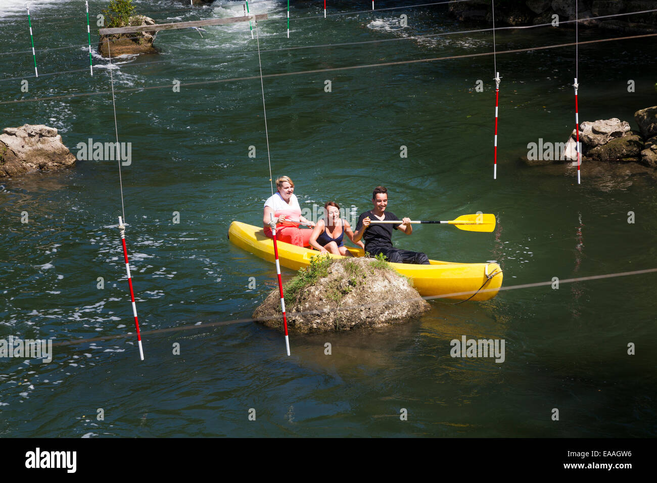 Three people navigate the Canoe slalom course with hanging gates on the ...
