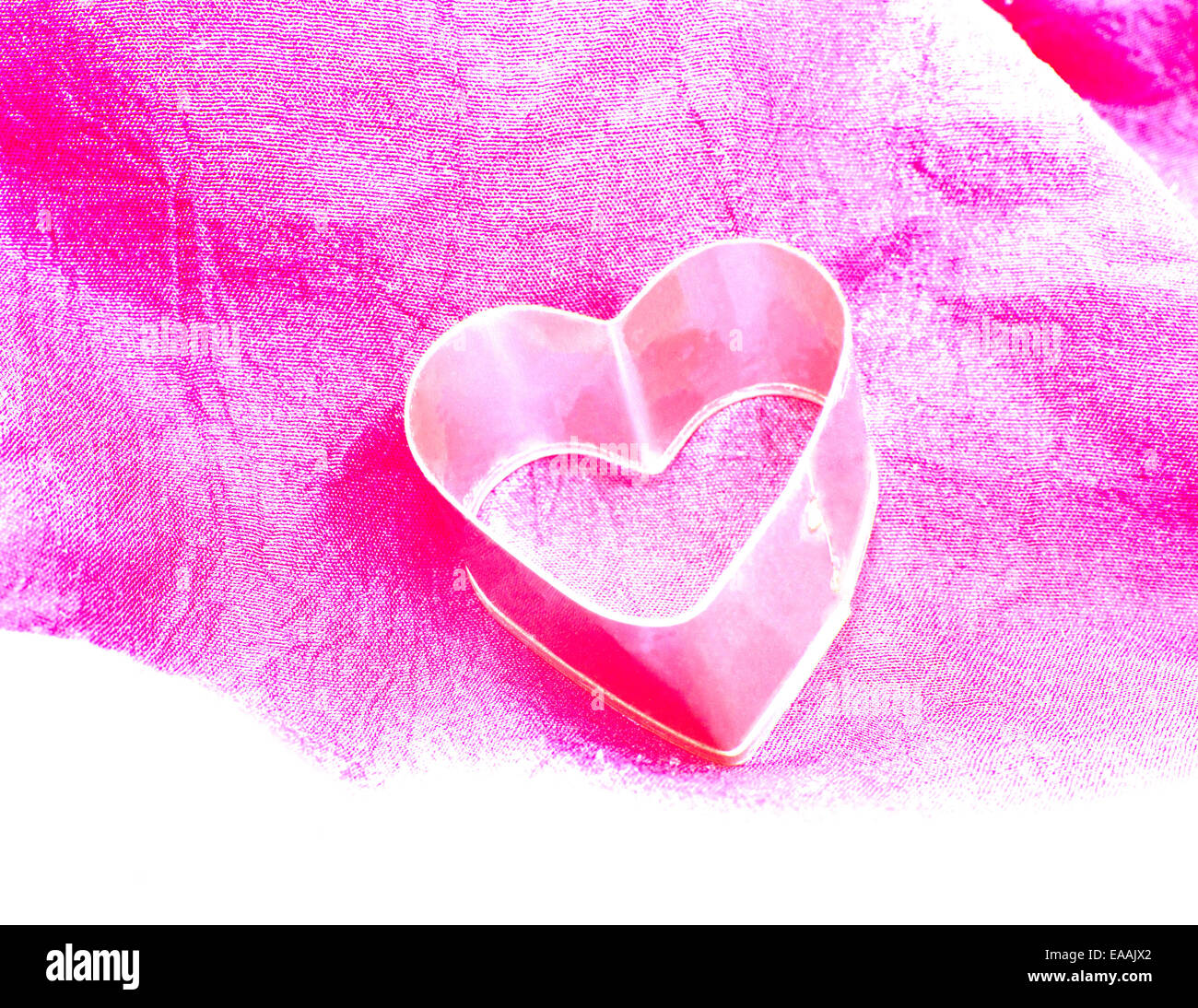 Pink heart. Pink baking tin in the shape of a heart on pink fabric ...