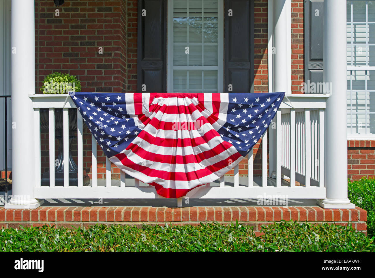Buntings hang from a front porch of an upscale, brick home in ...