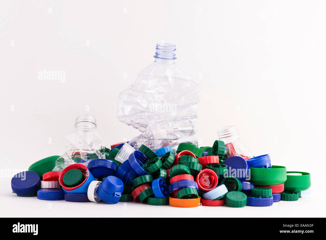 lots of plastic plugs with three crushed plastic bottles isolated on ...
