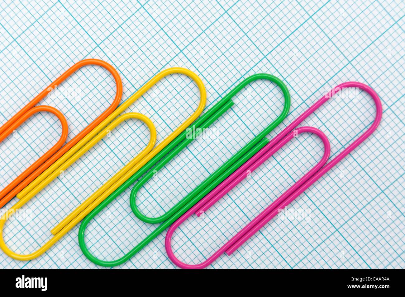Giant paper clips arranged on a graph paper background Stock Photo - Alamy