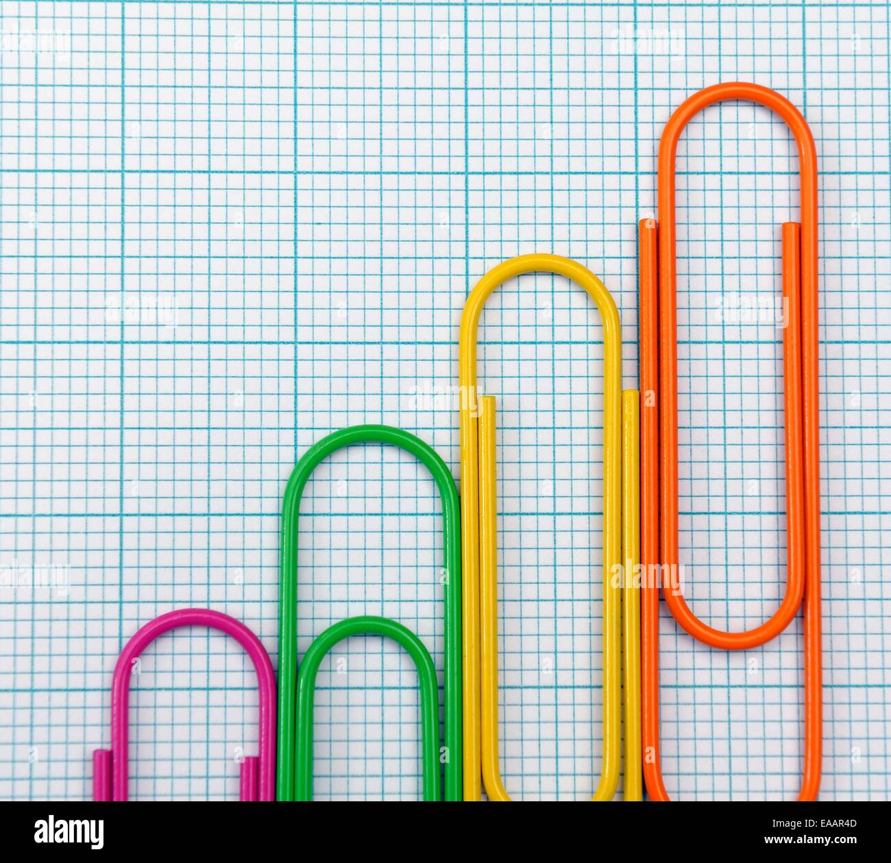 Giant paper clips arranged on a graph paper background Stock Photo - Alamy