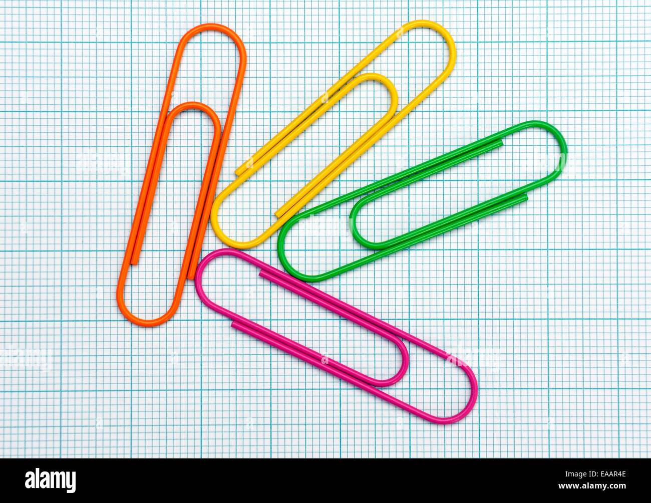 Giant paper clips arranged on a graph paper background Stock Photo - Alamy